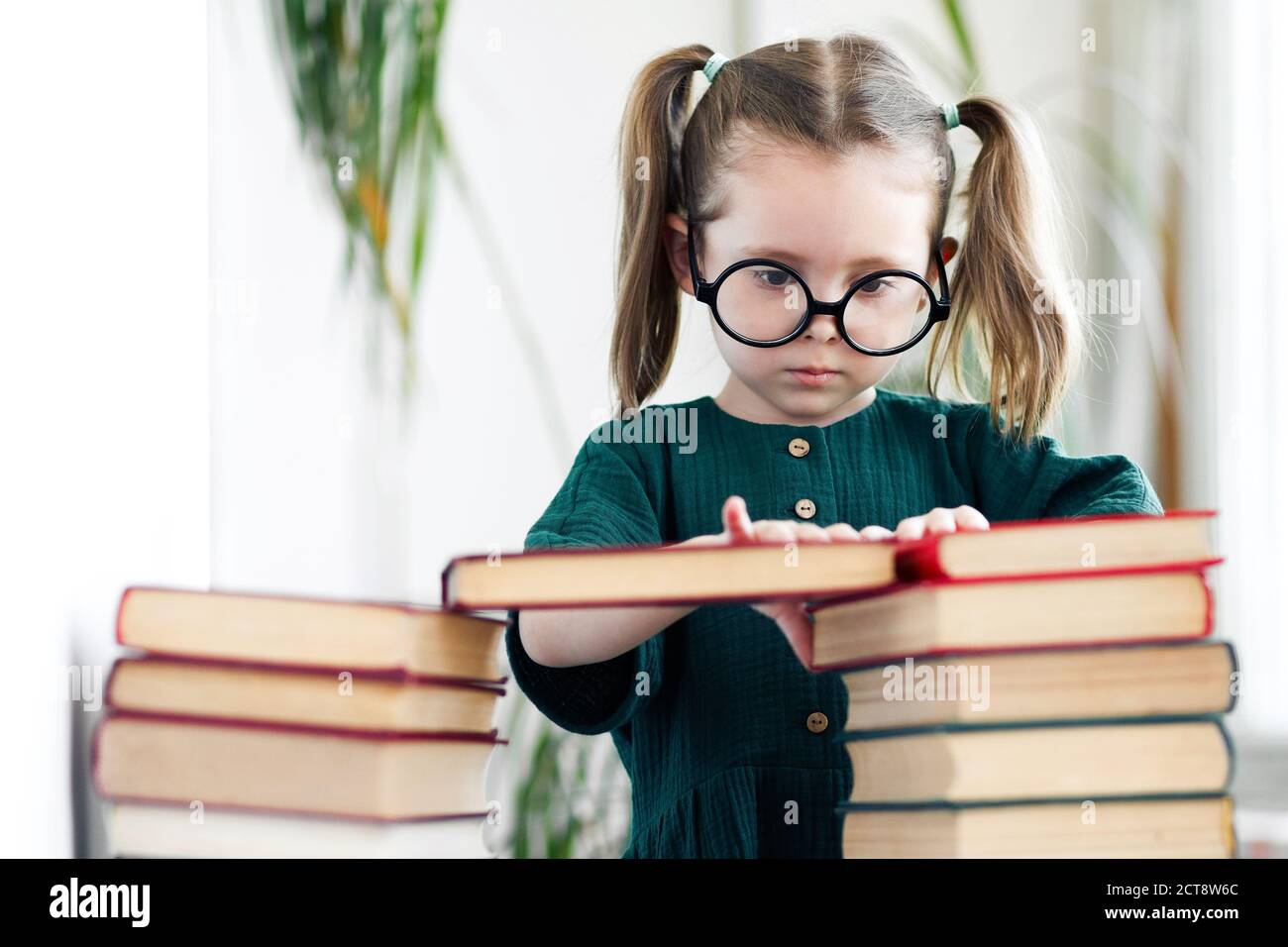 Caucasian little child girl in green dress and glasses procrastination ...