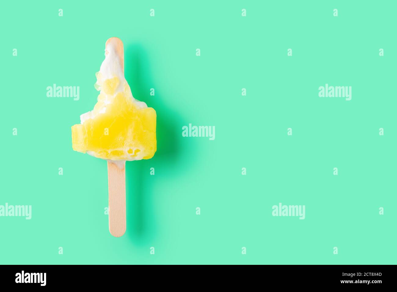 mostly eaten yellow popsicle on a light green background with copy ...