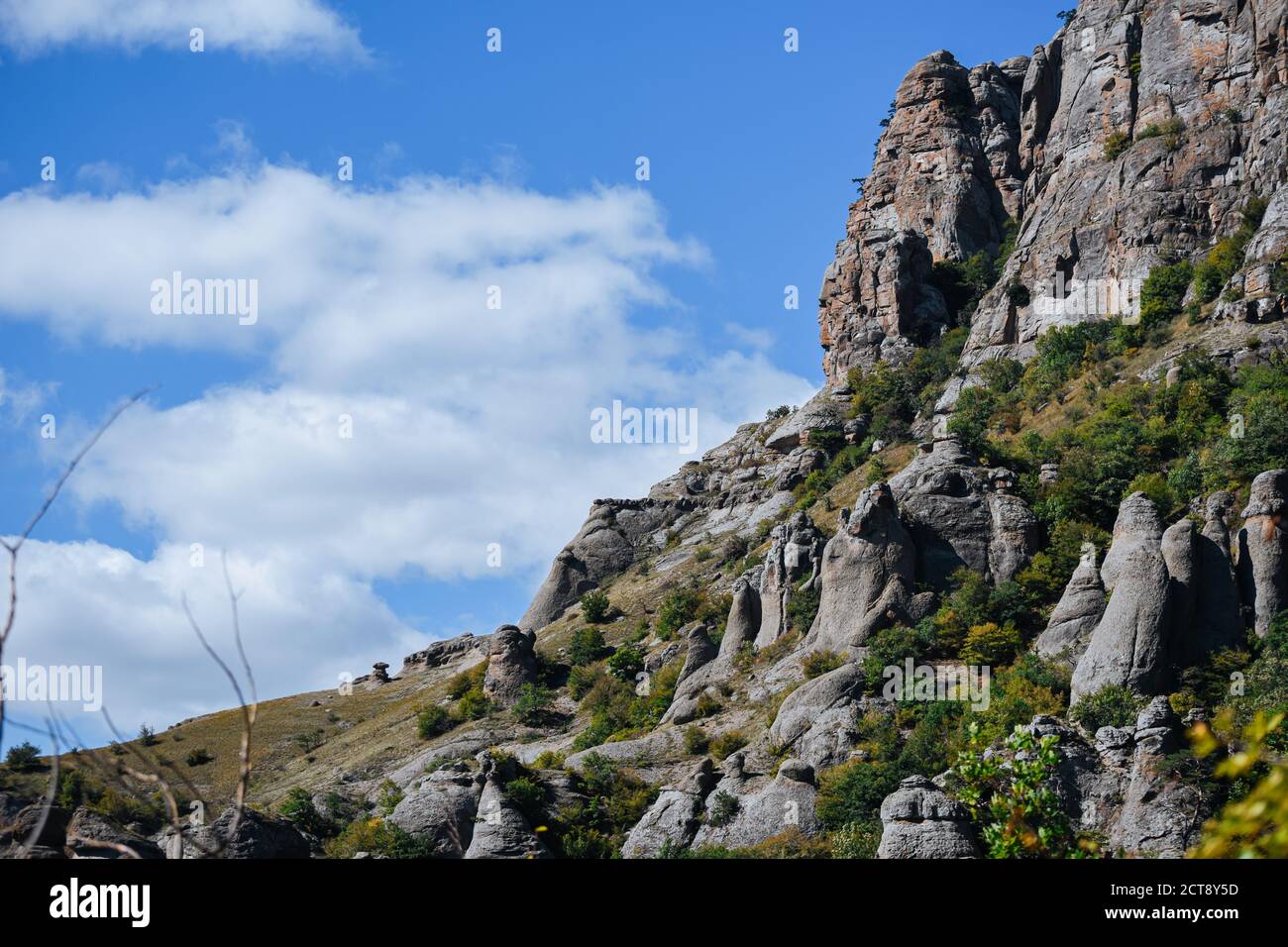 Stone hills and mountains with green trees and bushes against a blue ...