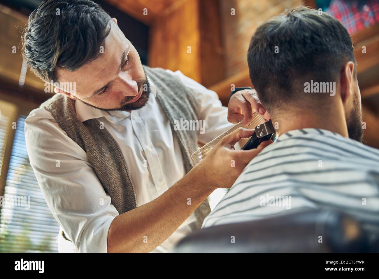 Professional barber taking a look at client hair Stock Photo - Alamy