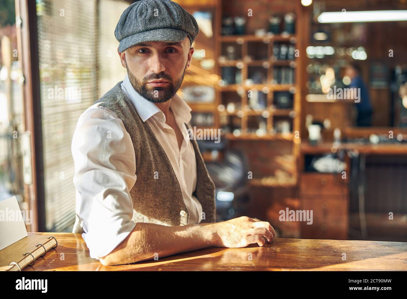 Handsome hairdresser wearing a vintage hat at barbershop Stock Photo ...