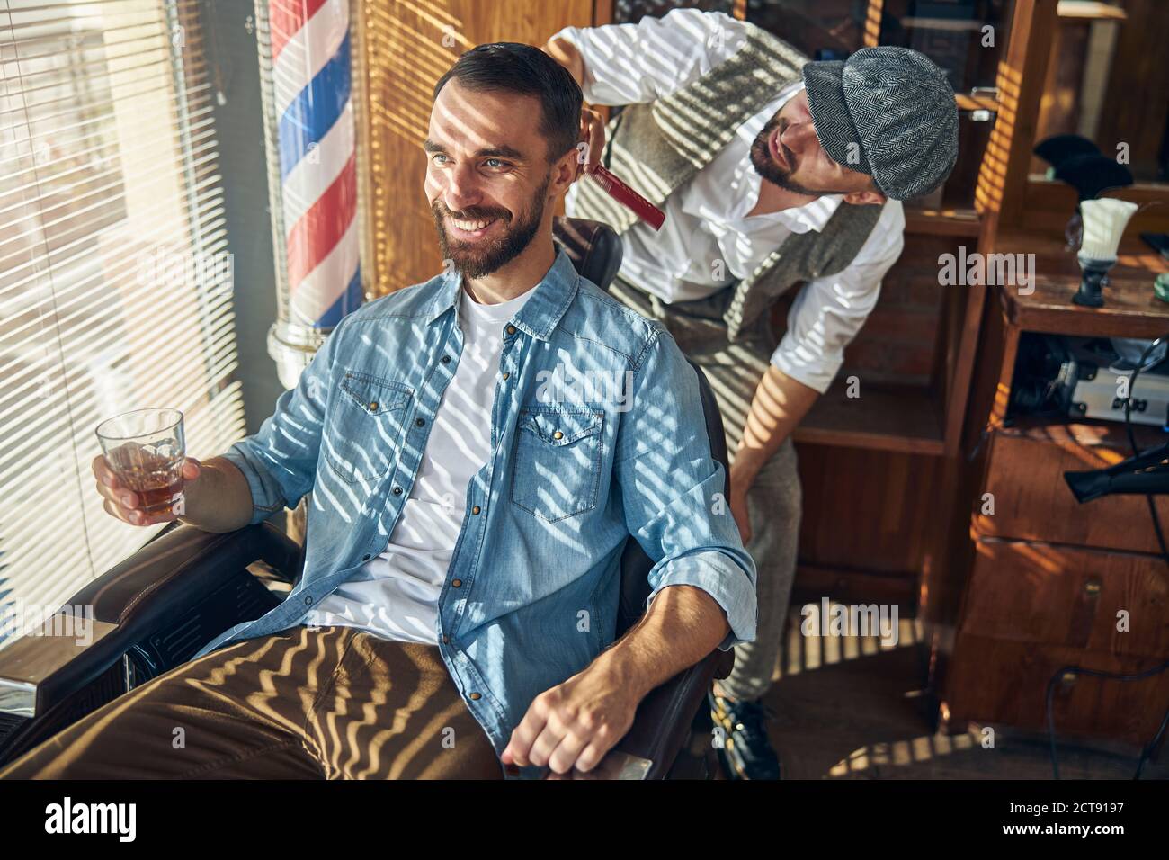 Barbershop customer enjoying his appointment with a glass of alcohol ...