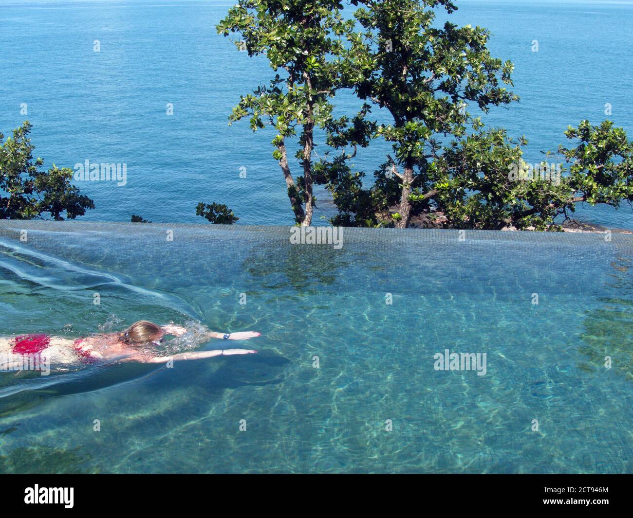 Young Western woman in a bikini swimming in an infinity pool at Six ...
