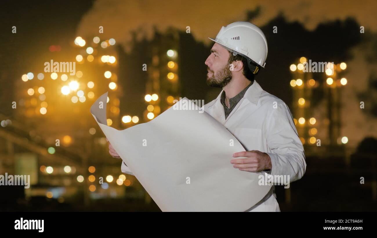 Engineer looking at blueprint at refinery Stock Photo - Alamy