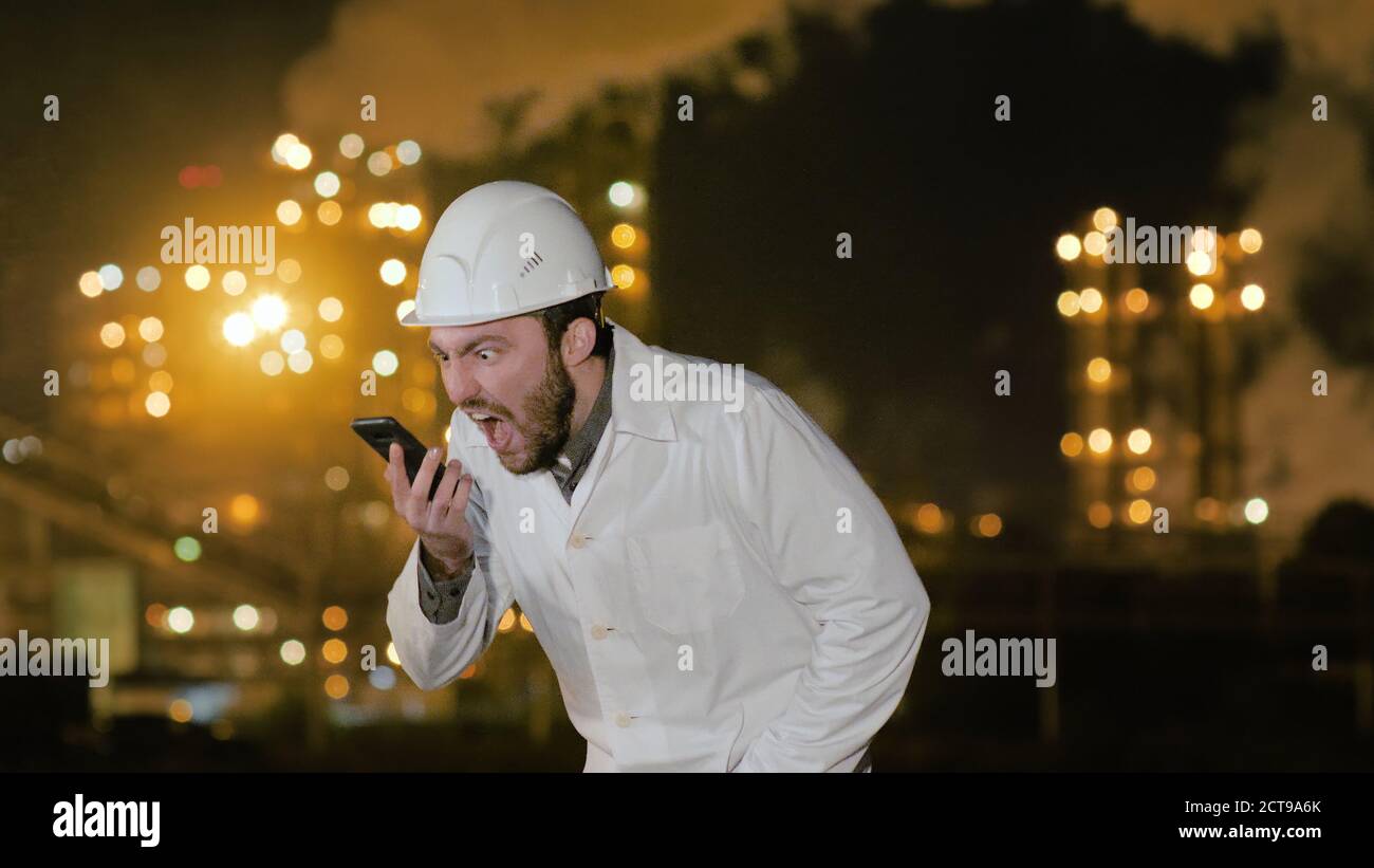 Young angry engineer in helmet and white robe shouting on phone Stock ...