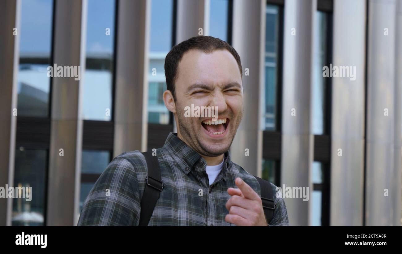 Young man looking at camera seriously and starts laughing Stock Photo ...