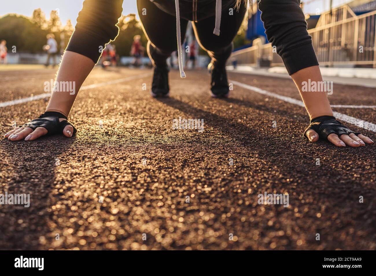Young athletic woman doing plank exercise on running track. Sunset ...