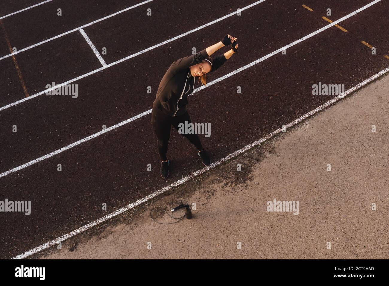 Active woman do stretching on the cycle track outdoors. She wears a ...