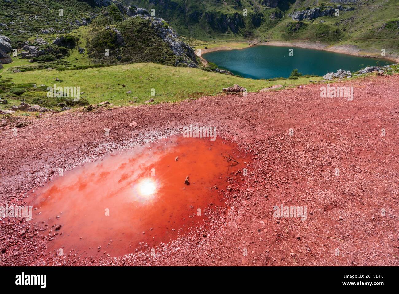 Red puddle with sun reflection and lake Stock Photo - Alamy