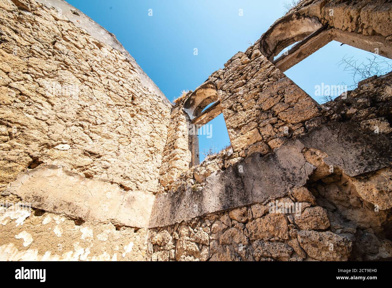 Old ruined and abandoned building with stone walls under blue sky. High ...