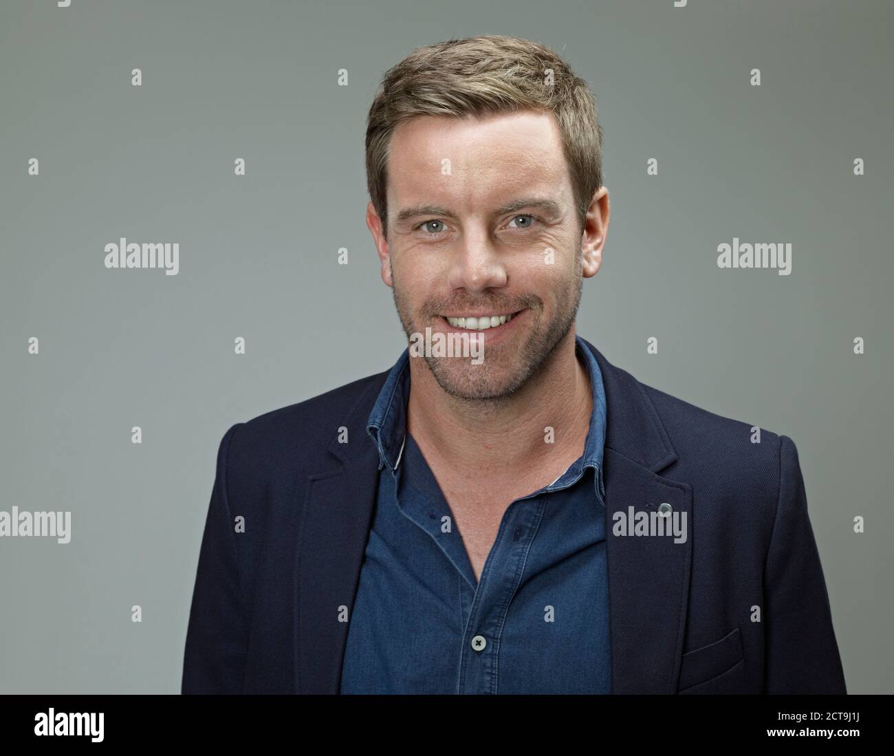Portrait of smiling man in front of grey background Stock Photo - Alamy