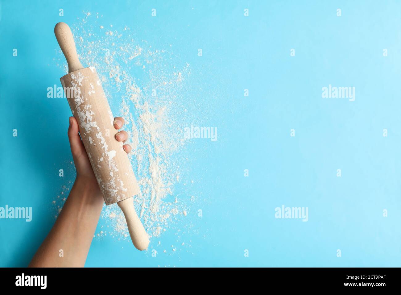 Female hand hold rolling pin on blue background Stock Photo - Alamy