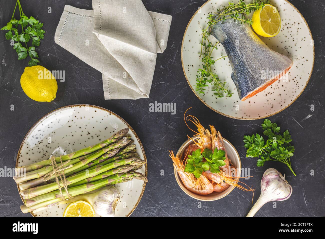 Trout fish surrounded parsley, lemon, shrimp, prawn, asparagus in ...