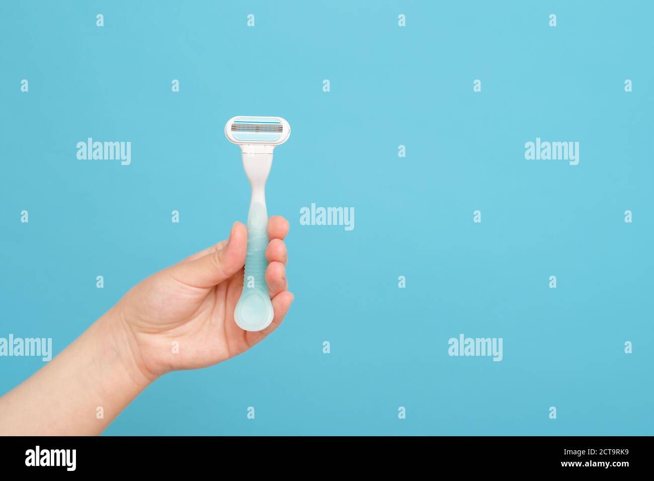 razor in female hand on blue background Stock Photo - Alamy