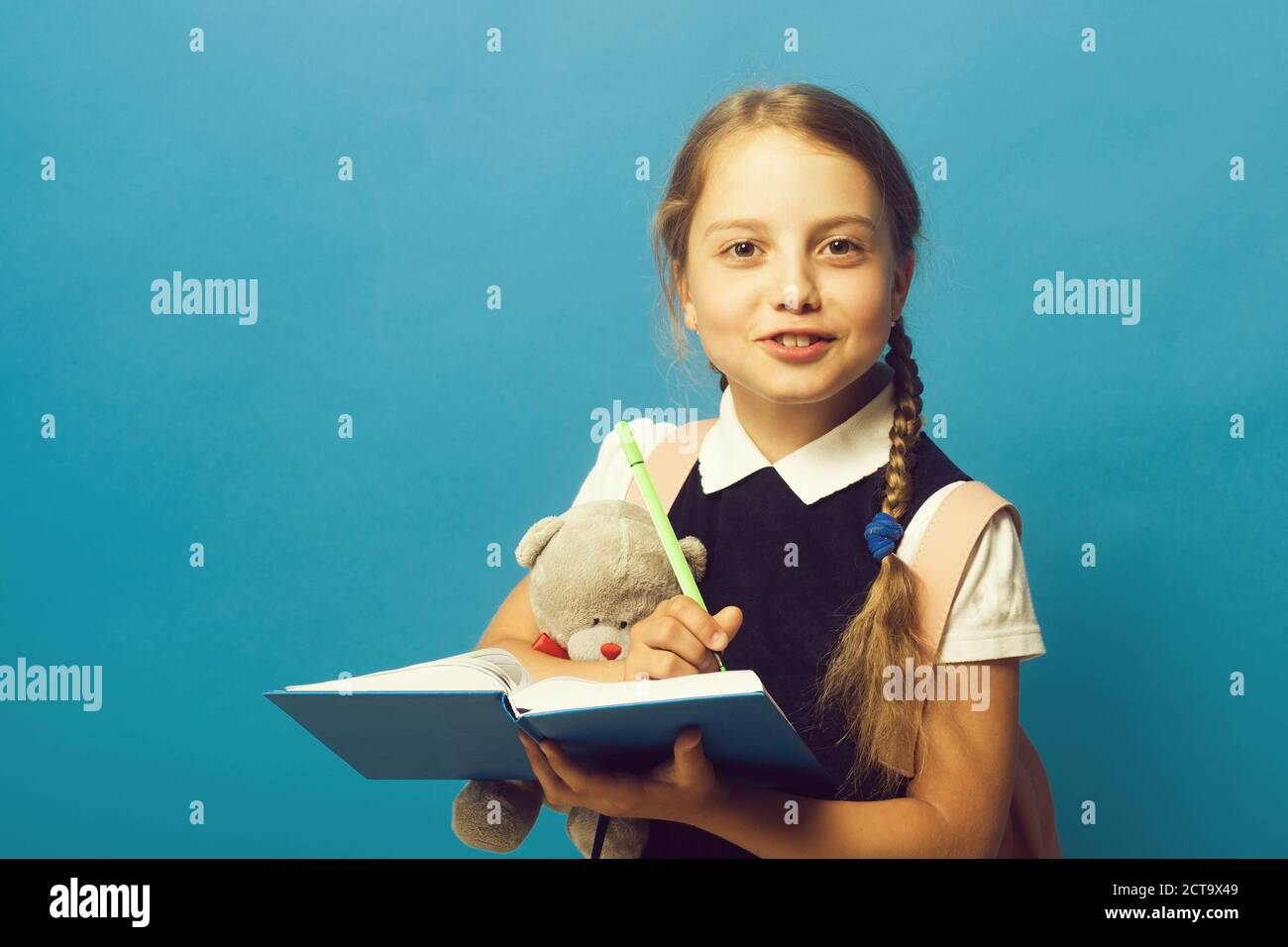 Girl with braids and happy face. Kid in school uniform isolated on blue ...
