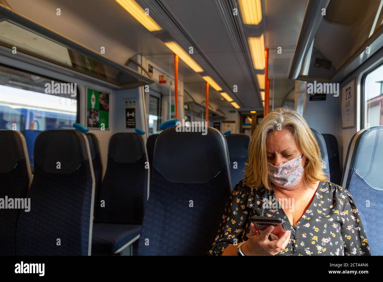 A middle aged woman sitting alone in a train carriage wearing a face ...