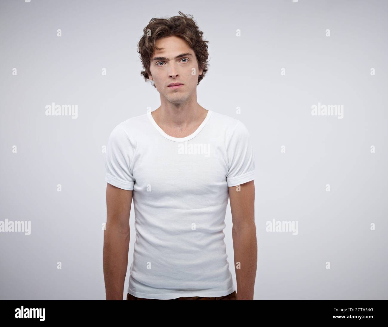 Portrait of serious looking man wearing white t-hirt in front of white ...