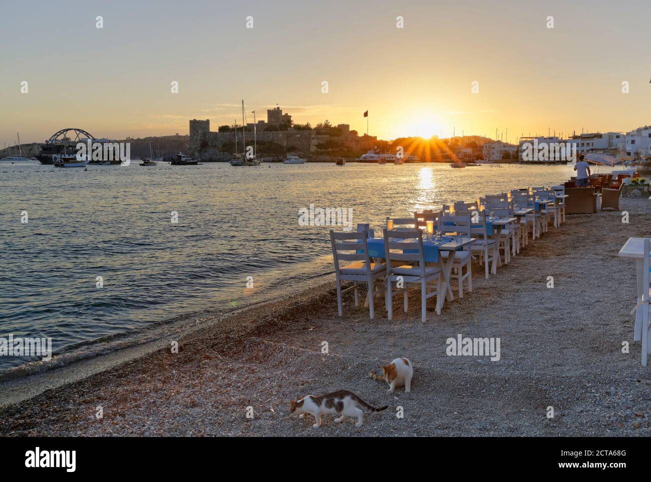Turkey, Bodrum, Castle of St. Peter and restaurant on beach at sunset ...