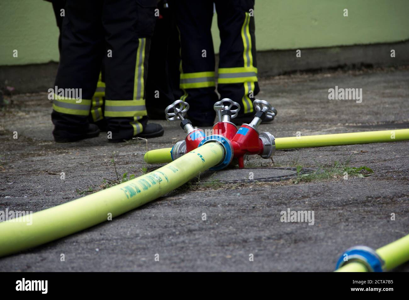 Germany, Bavaria, Firehose with valve, Firefighters in the background ...