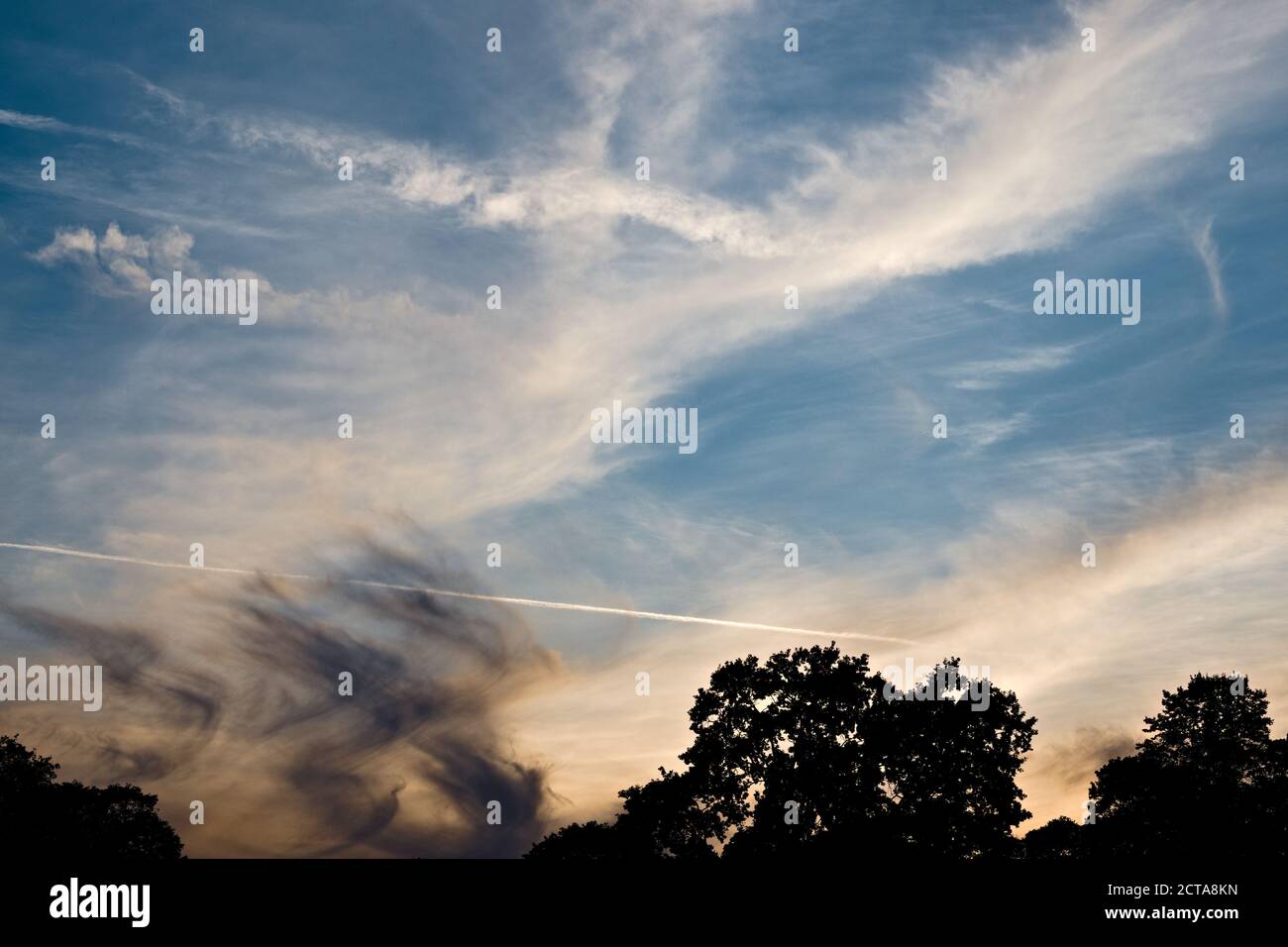 Rich blue evening sky full of wispy clouds and an orange horizon Stock ...