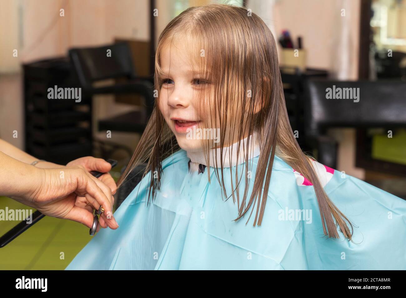 hair cutting process. beautiful little red-haired girl at the barber ...