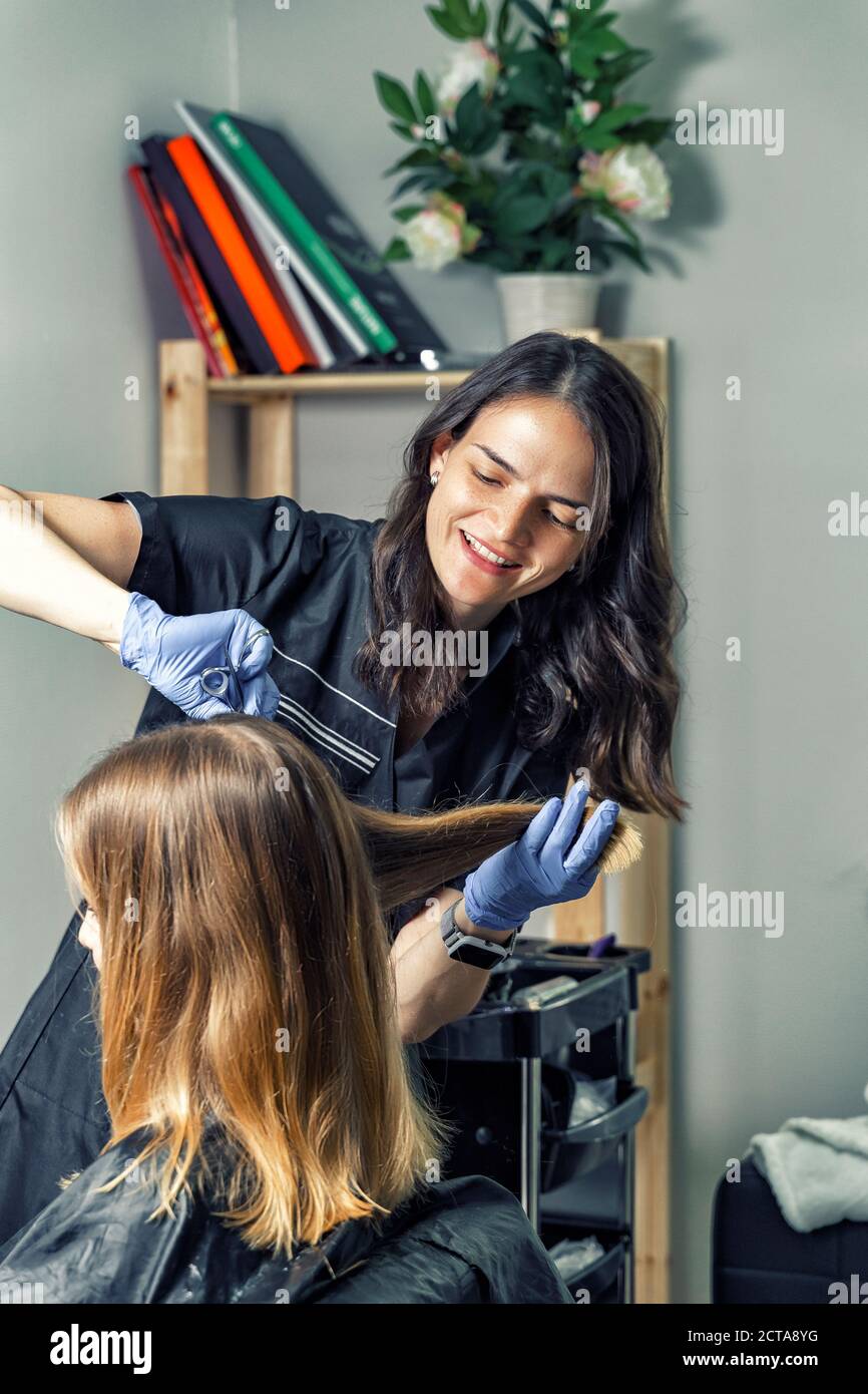 smiling beautiful hairdresser doing hairstyle to young girl Stock Photo ...