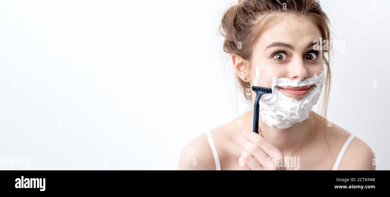 Beautiful young caucasian woman shaving her face by razor on white ...