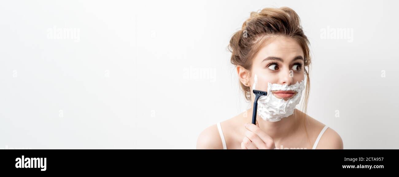 Beautiful young caucasian woman shaving her face by razor on white ...