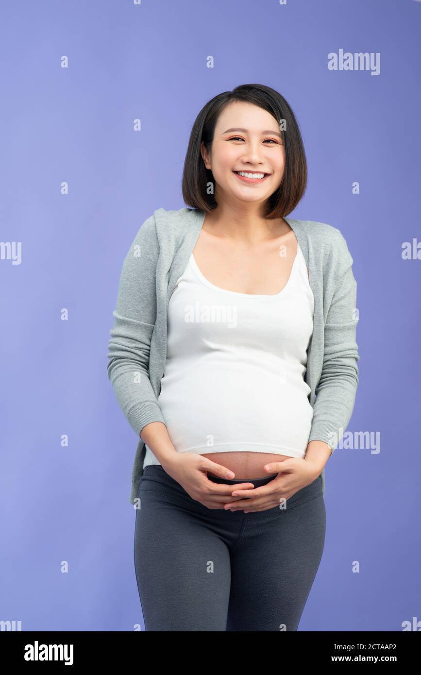 Happy pregnant woman posing on color background Stock Photo - Alamy