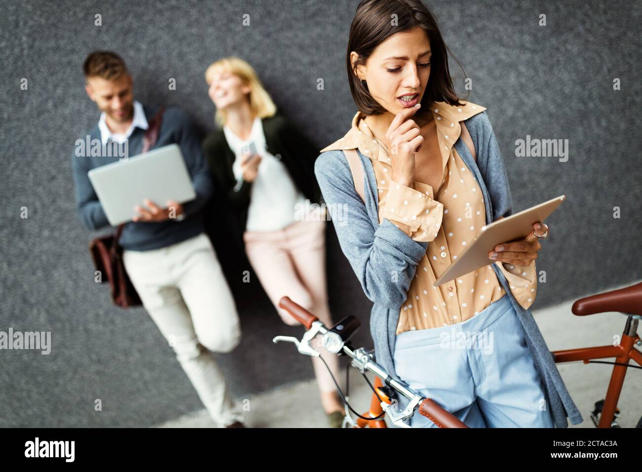 Group of young business people holding different digital devices ...