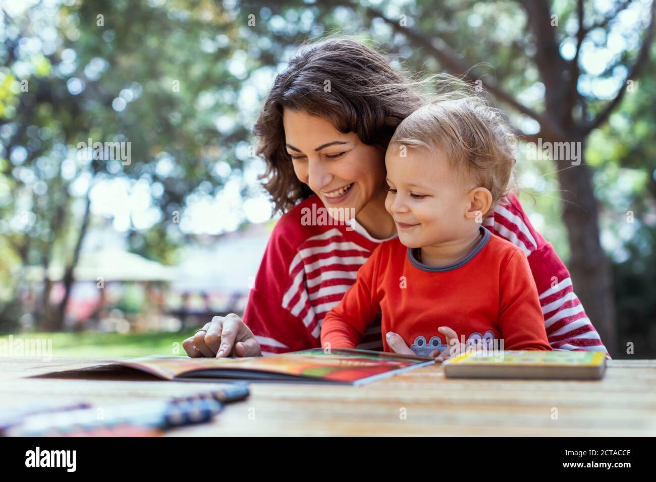 Mother and Son Reading Books at the Garden, with Crayons on the Picnic ...
