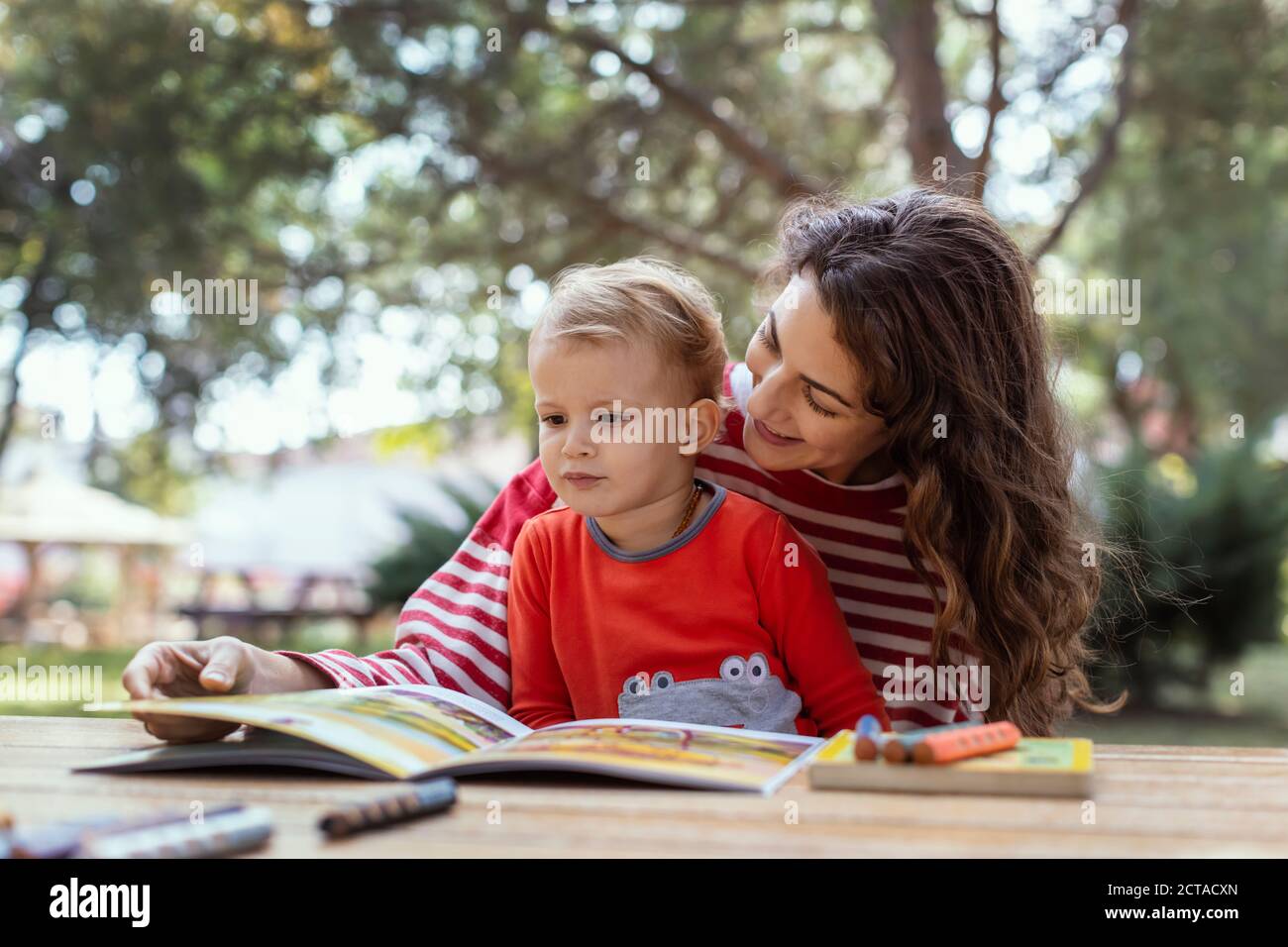 Mother and Son Reading Books at the Garden, with Crayons on the Picnic ...