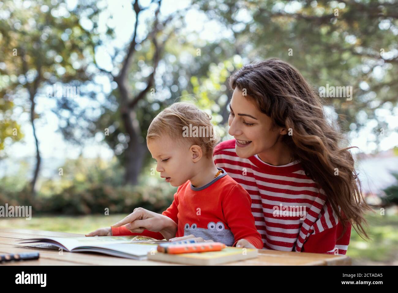 Mother and Son Reading Books at the Garden, with Crayons on the Picnic ...