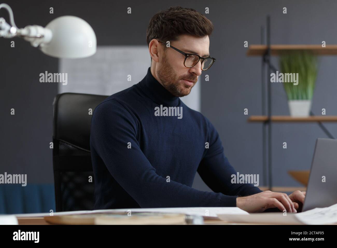 Architect working in office with laptop. Engineer thinks over ...