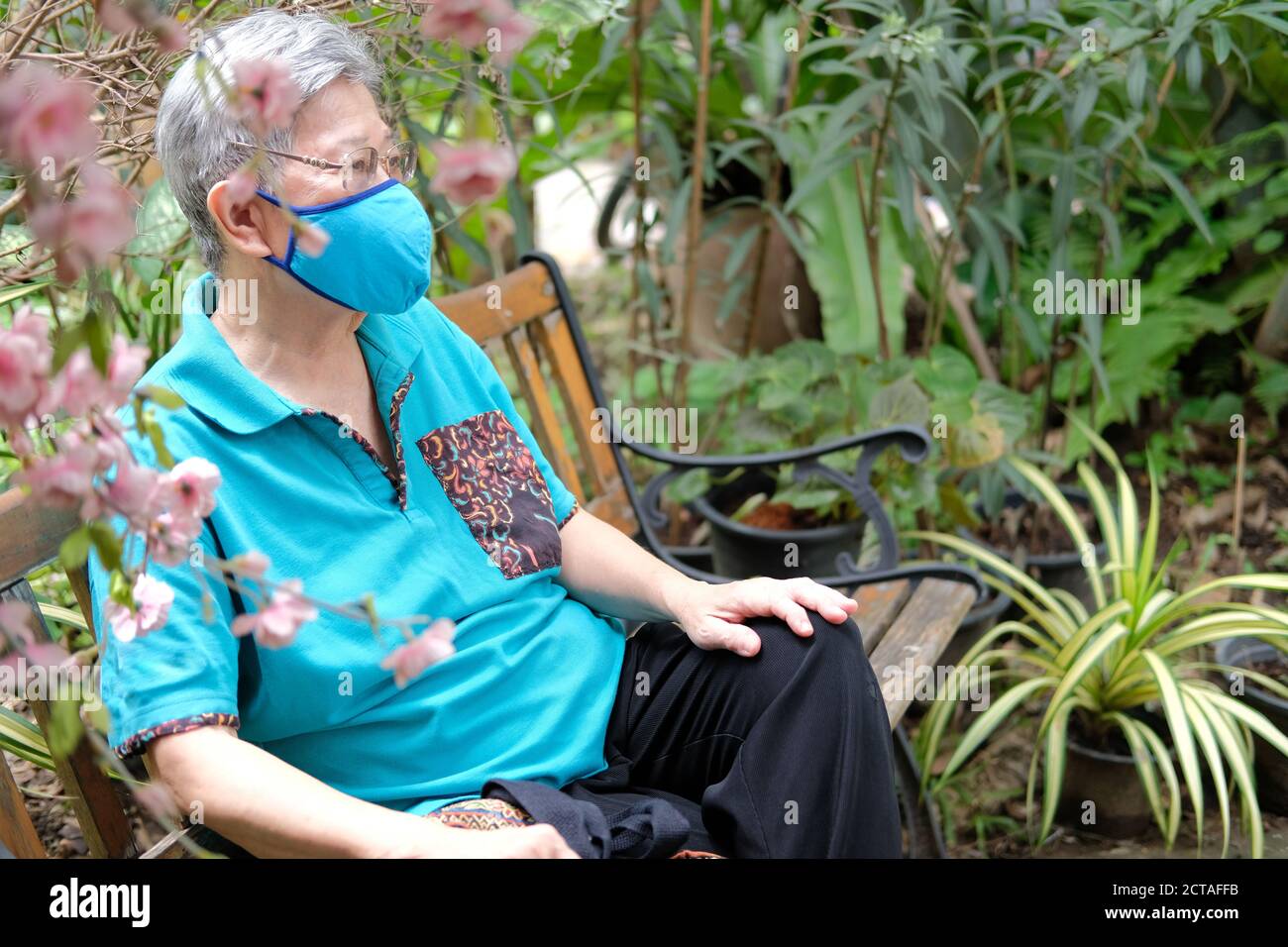 elder woman wearing facial mask resting in garden. asian elderly female ...