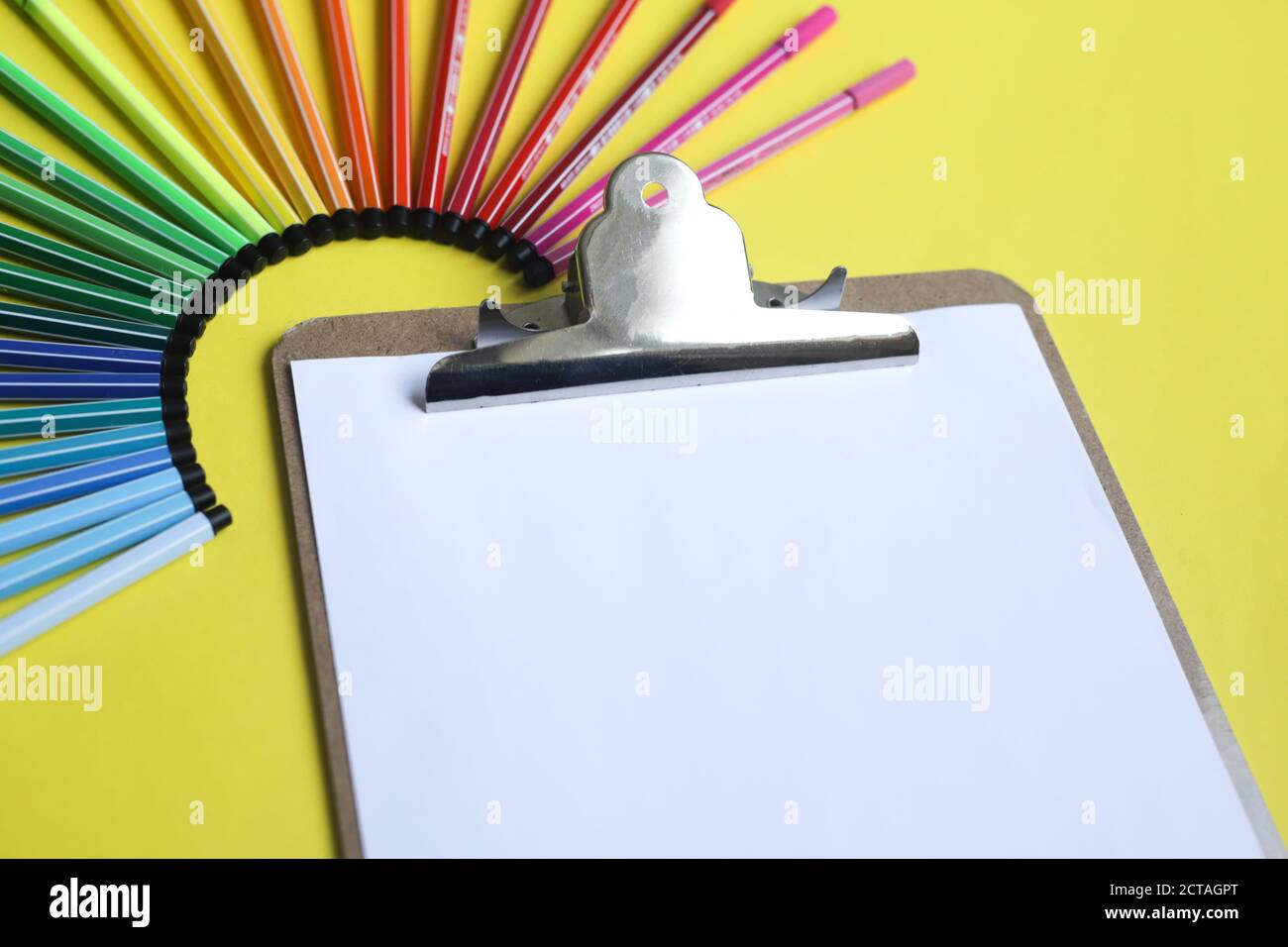Shot of a drawing board with colored pencils on a yellow background ...