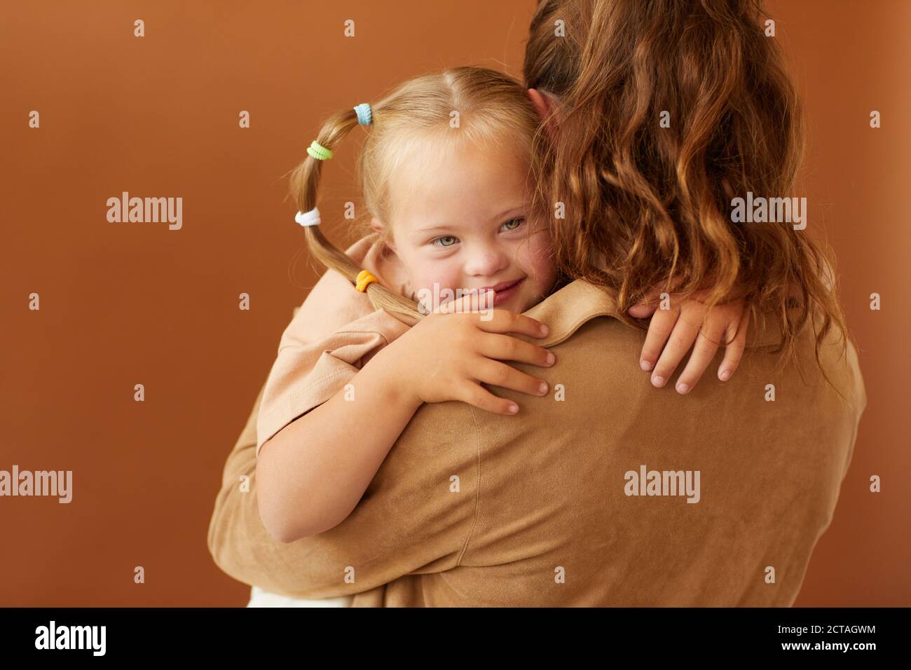 Back view portrait of mother holding happy daughter with down syndrome ...