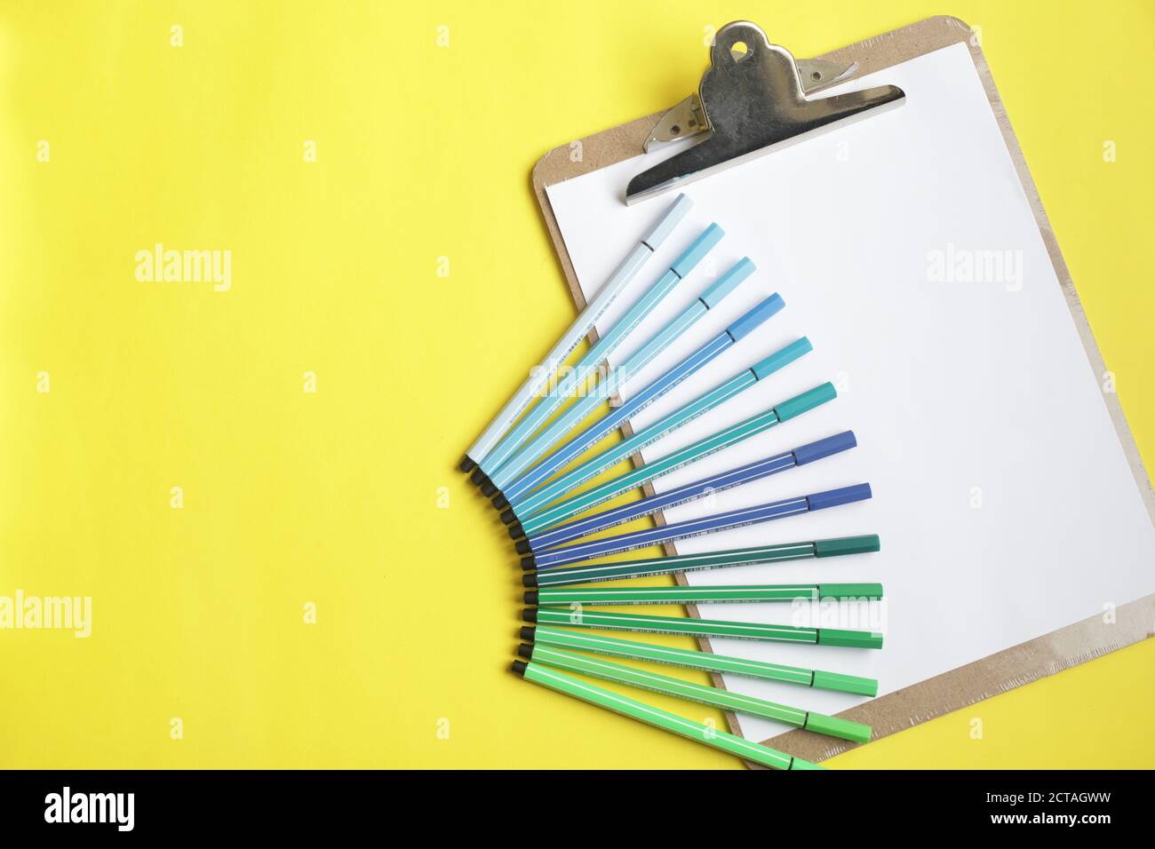 Shot of a drawing board with colored pencils on a yellow background ...