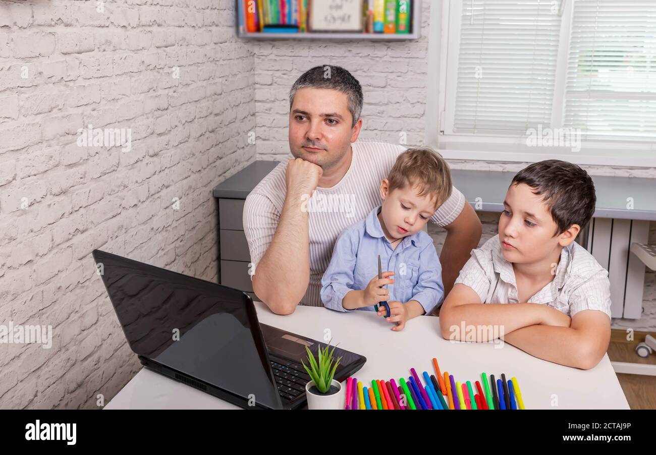 Father works with children on laptop at home office. Working from home ...