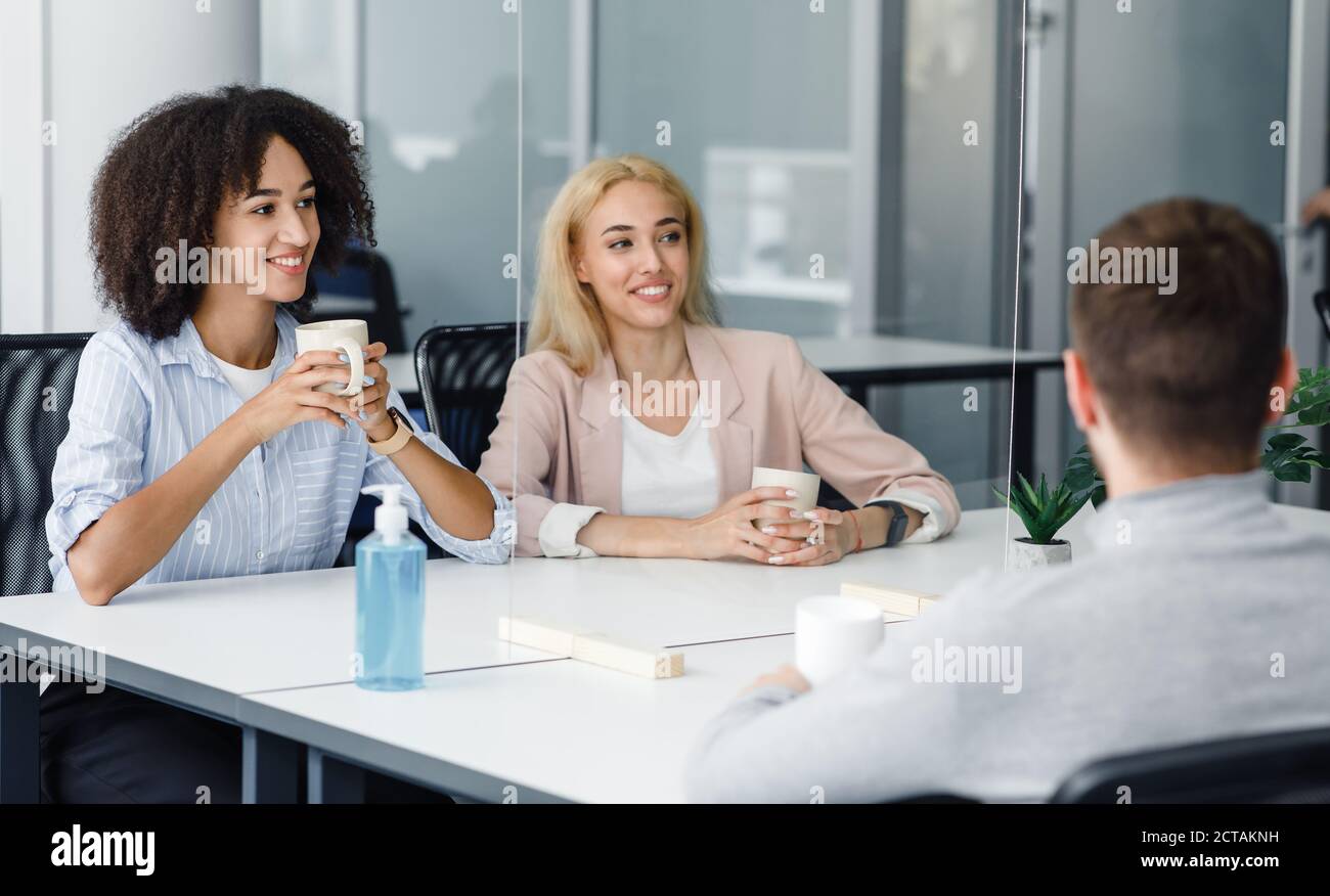 Smiling european and african american businesswomen with cups ...