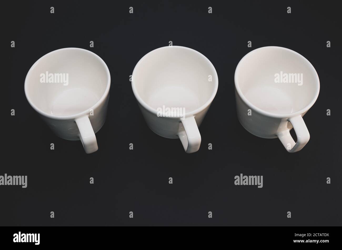 High angle shot of three empty cups on a black surface Stock Photo - Alamy