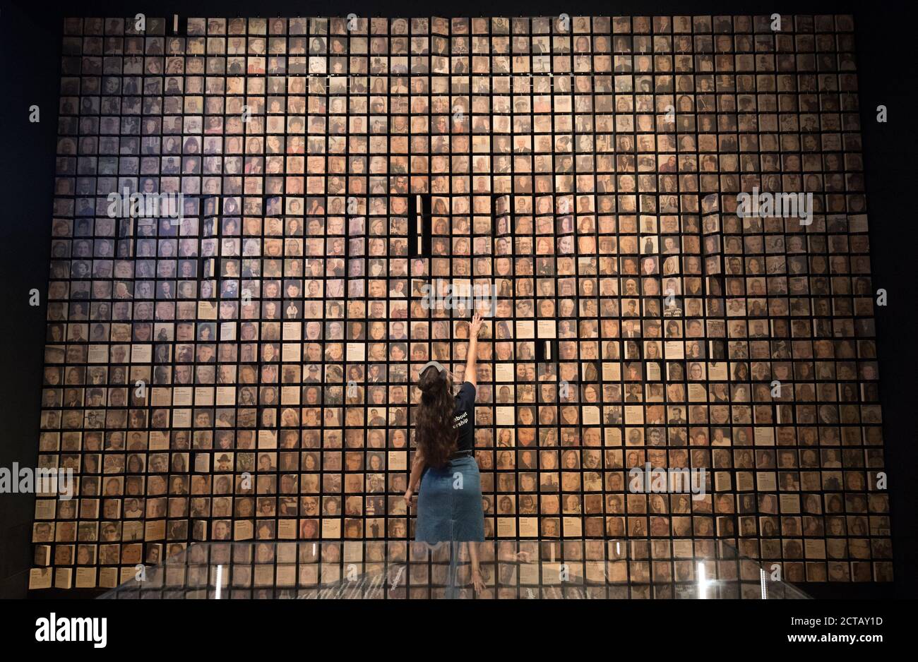 A staff member looks at a wall of faces of descendants related to the ...