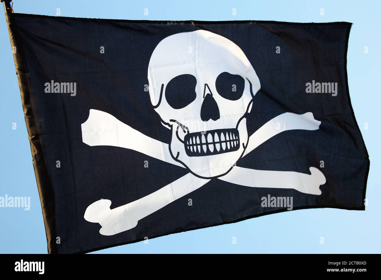 Jolly Roger scull and crossbones pirate flag flying on a clear blue sky ...