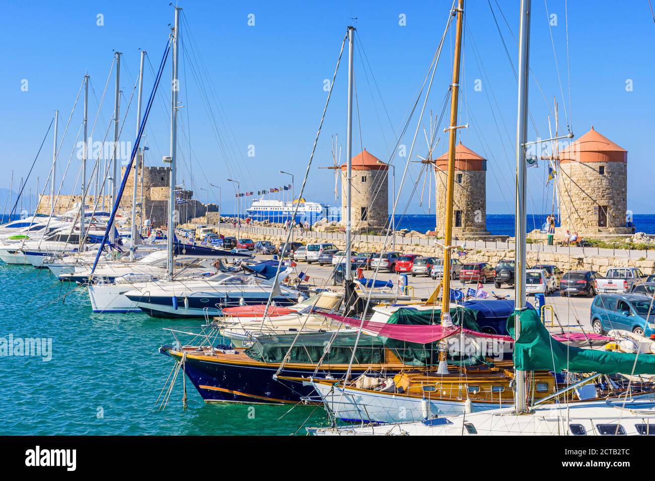 Yachts moored along the windmill lined jetty of Mandraki harbor, Rhodes ...