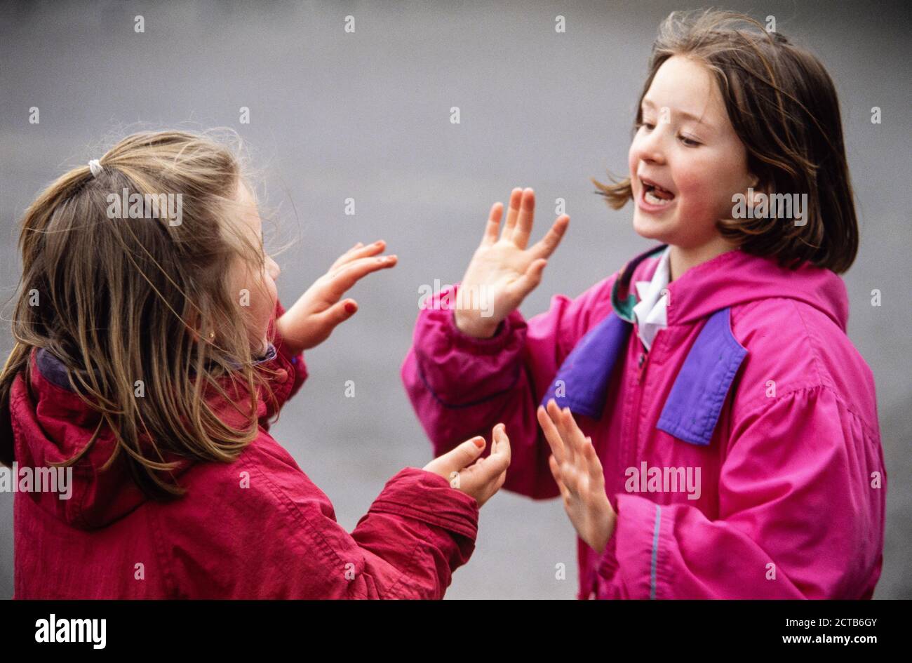 Two girls playing a breaktime clapping game in the playground at ...