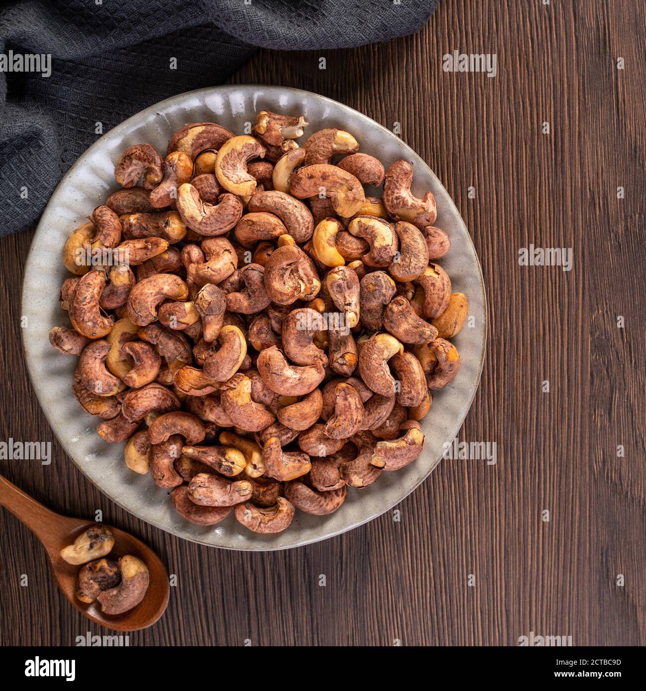 Cashew nuts with peel in a plate on wooden tray and table background ...