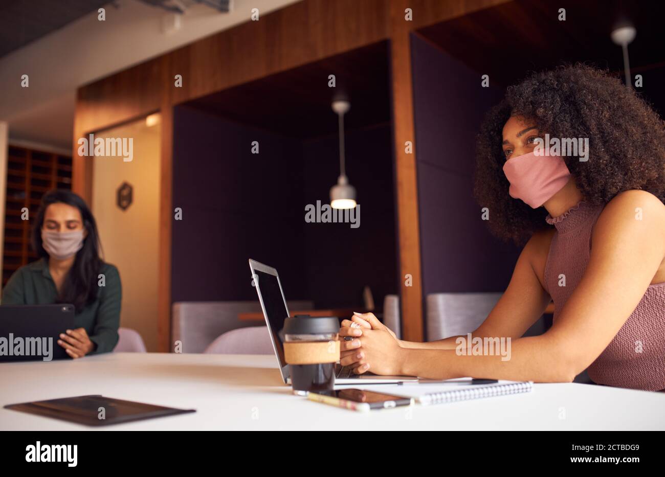 Businesswomen Wearing Masks Having Socially Distanced Meeting In Office ...