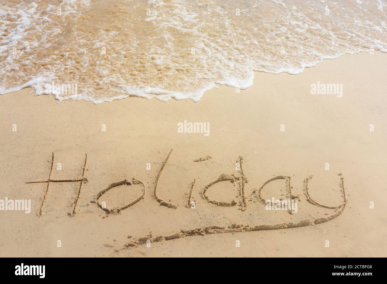 The word holiday written in the sand at the beach Stock Photo - Alamy