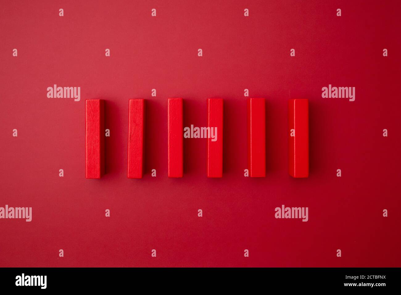 standing red domino blocks in red background Stock Photo - Alamy