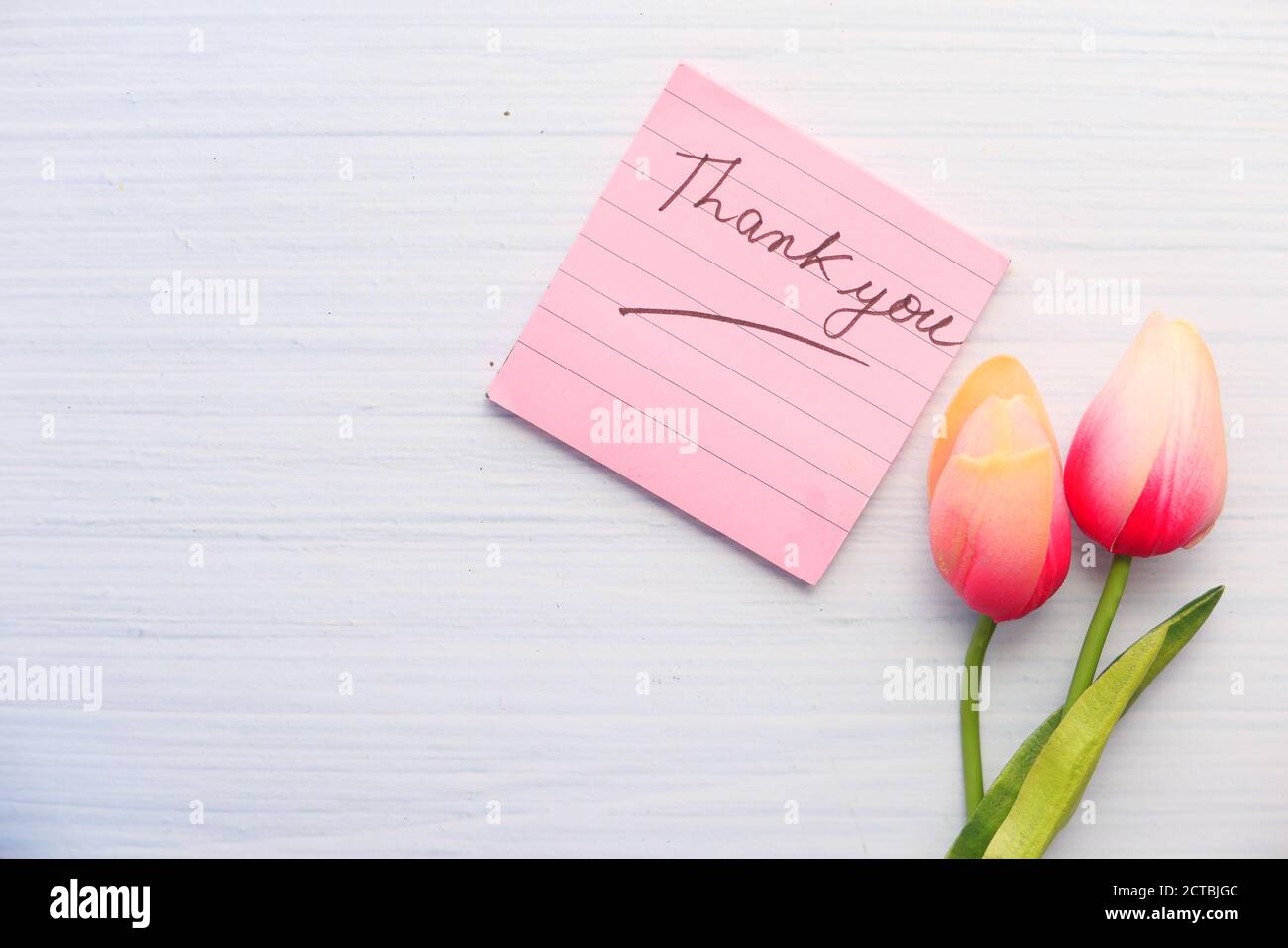 thank you message on sticky note with tulip flower on white background ...